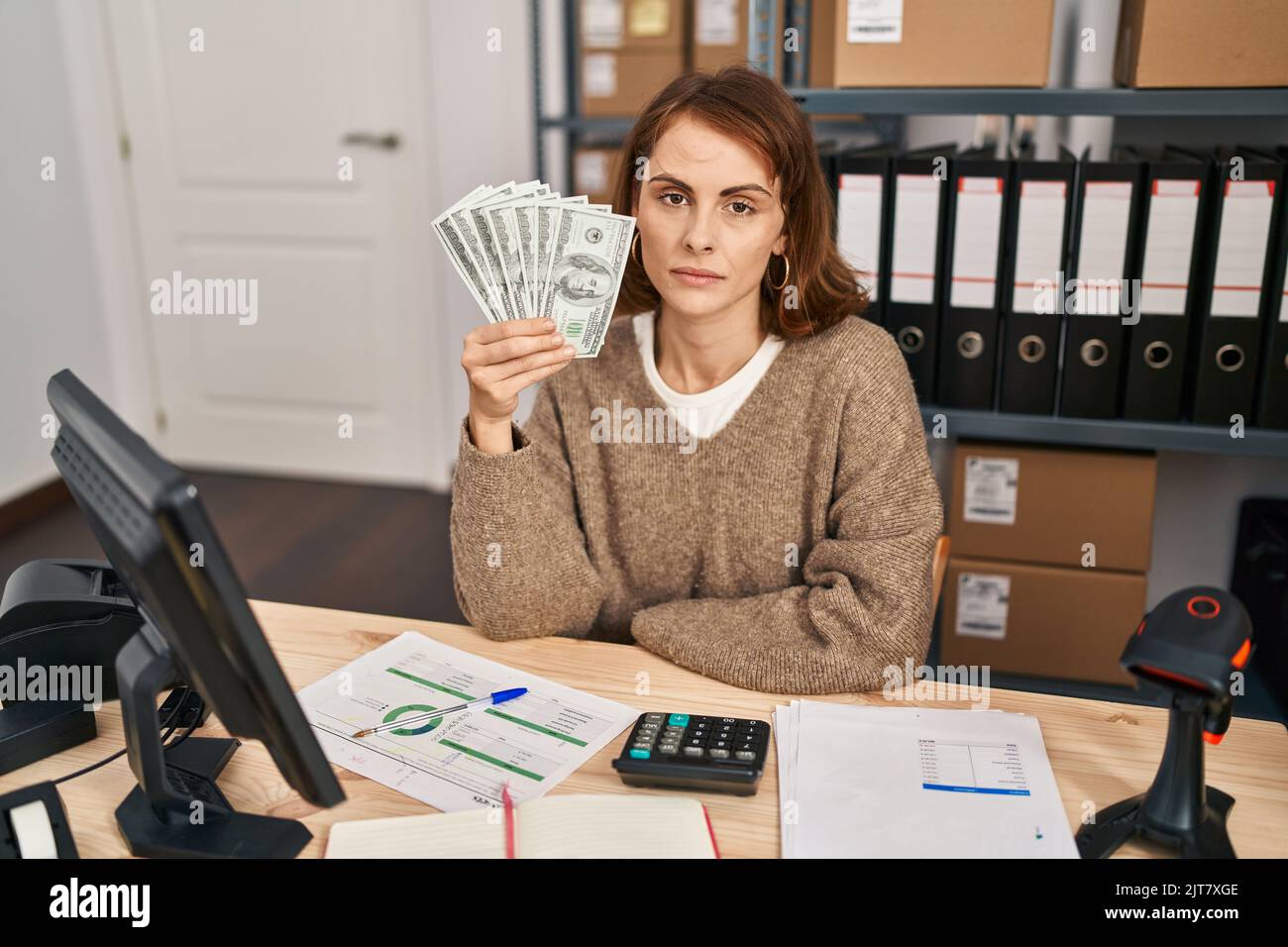 Young beautiful woman working at small business ecommerce holding money ...
