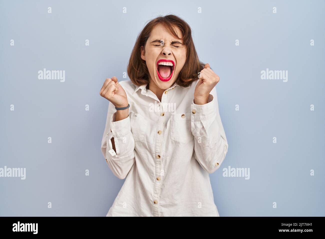 Young beautiful woman standing casual over blue background excited for ...