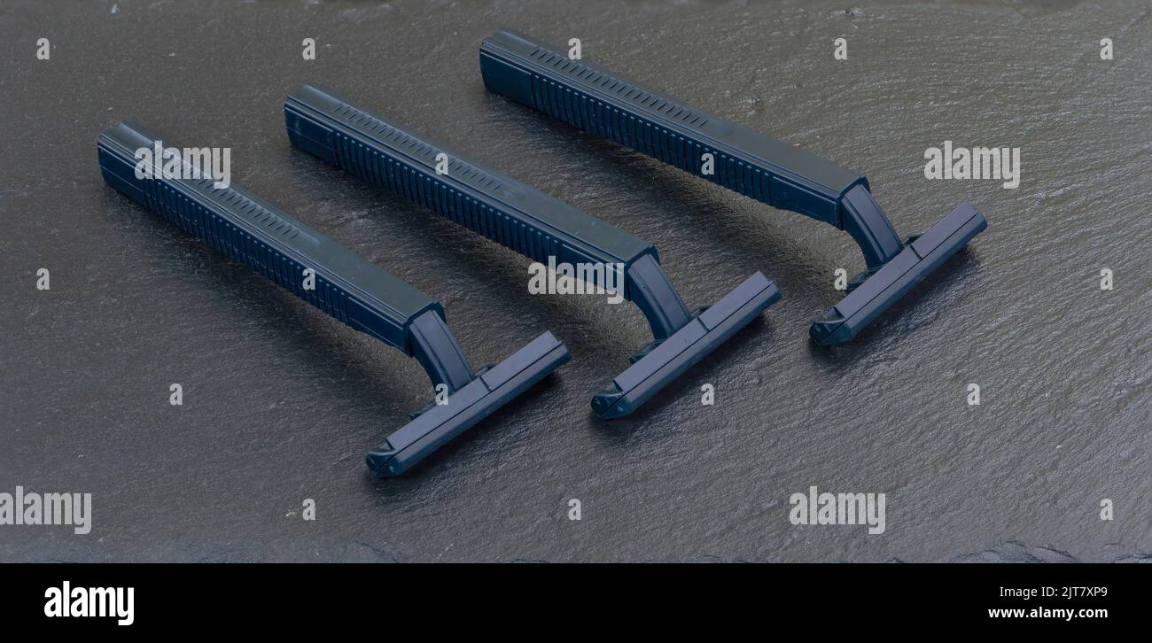 three disposable razors on dark stone background Stock Photo - Alamy