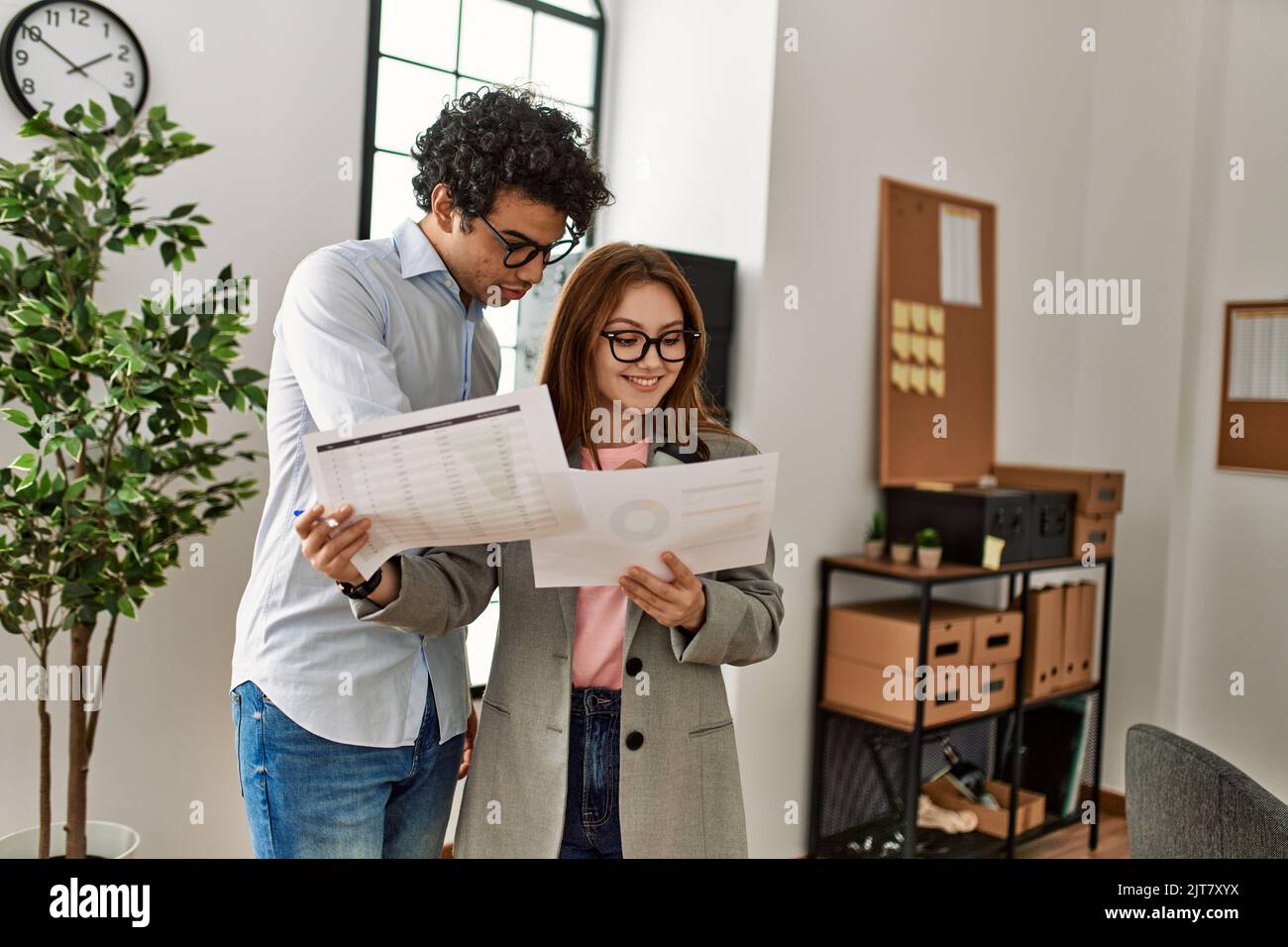 Two business workers smiling happy reading paperwork working at the ...