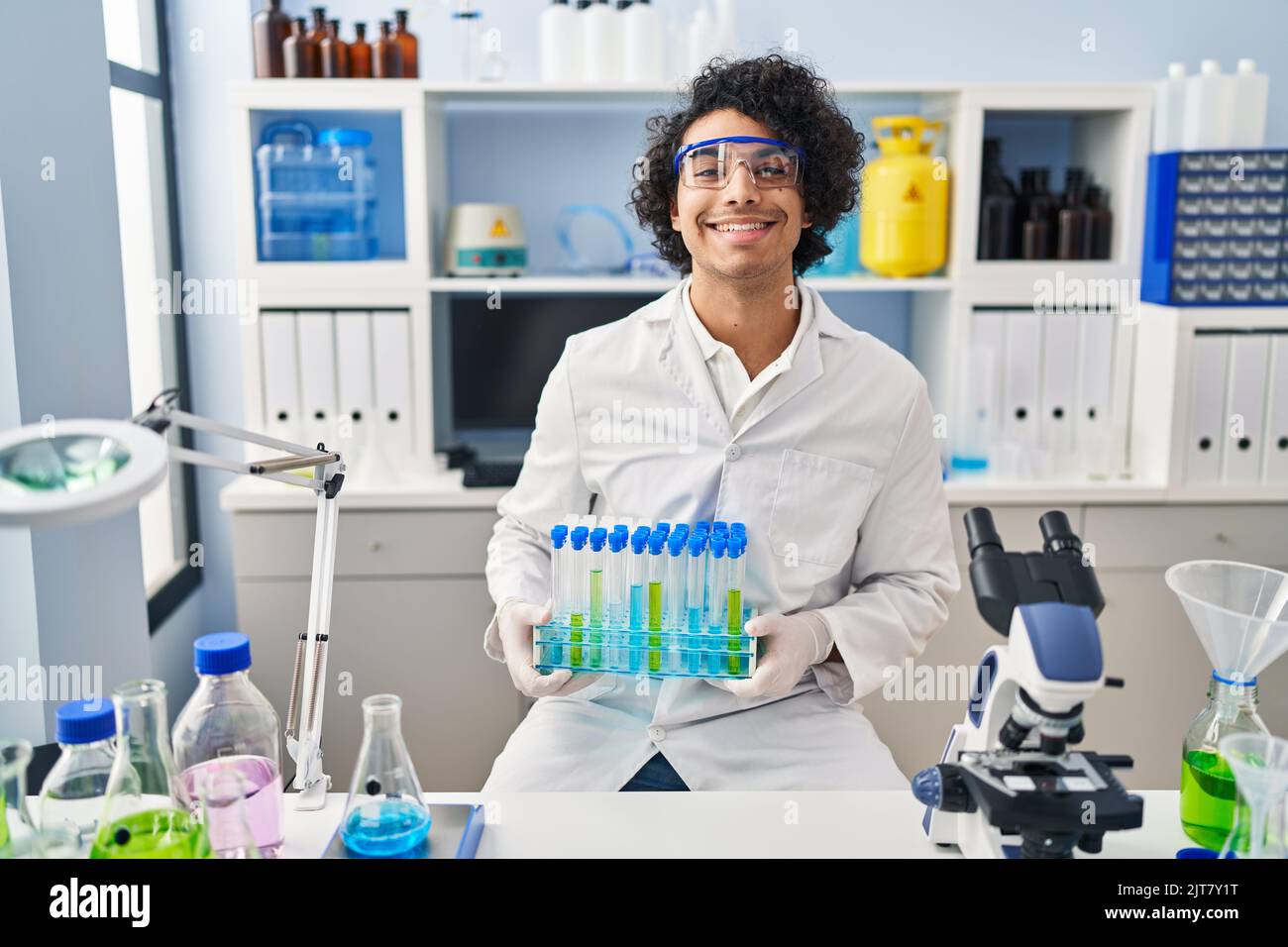 Hispanic man with curly hair working at scientist laboratory looking ...
