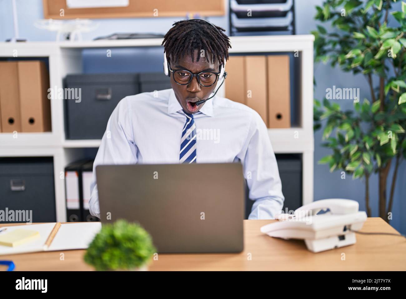 African man with dreadlocks wearing call center agent headset scared ...