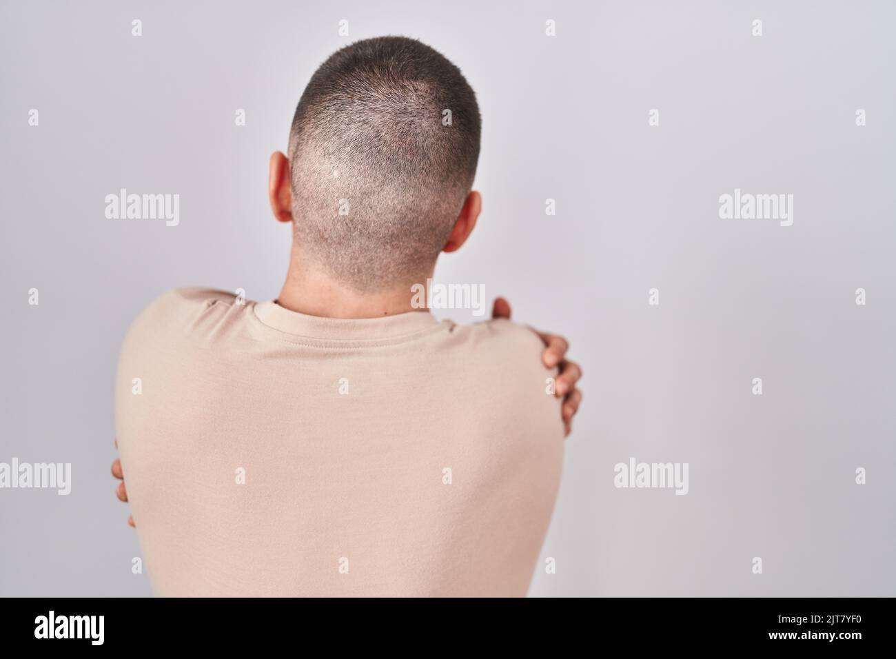Young man standing over isolated background hugging oneself happy and ...