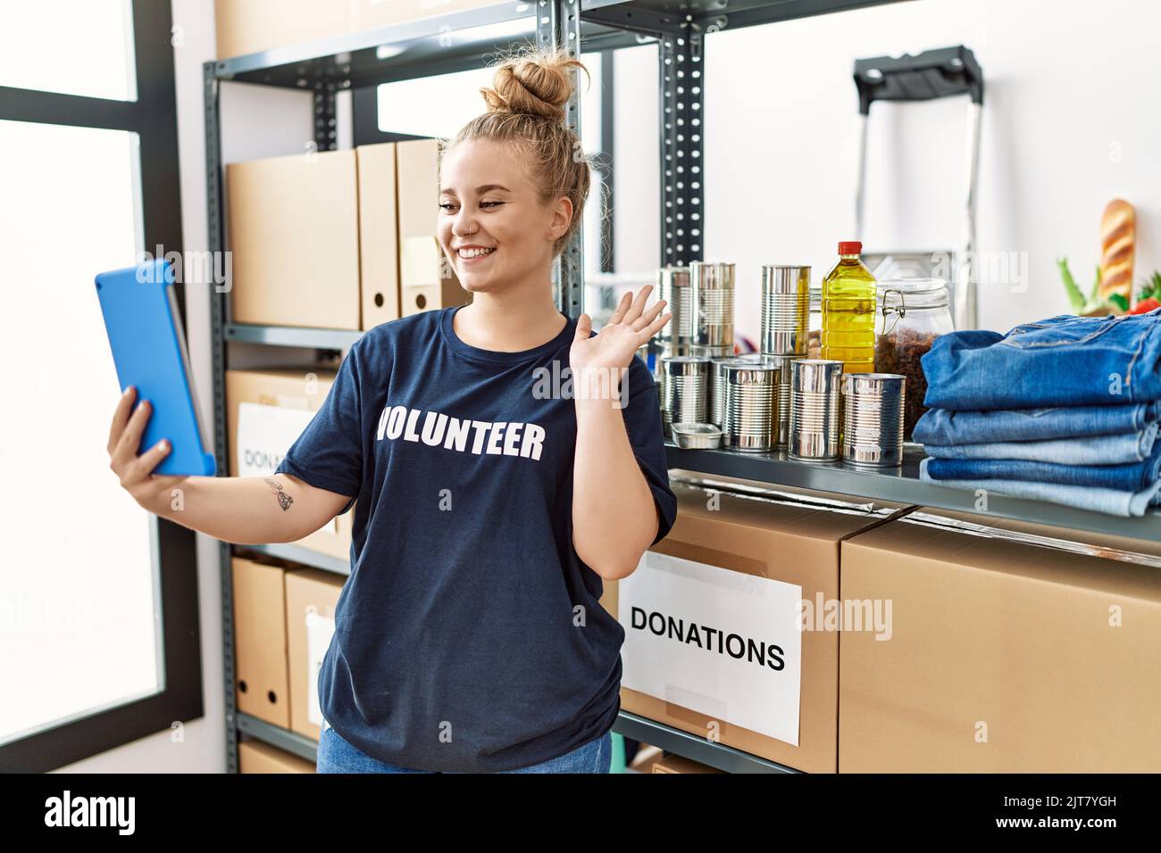 Young blonde girl wearing volunteer uniform having video call at ...