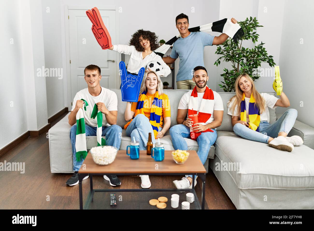 Group of young friends watching and supporting soccer match at home ...