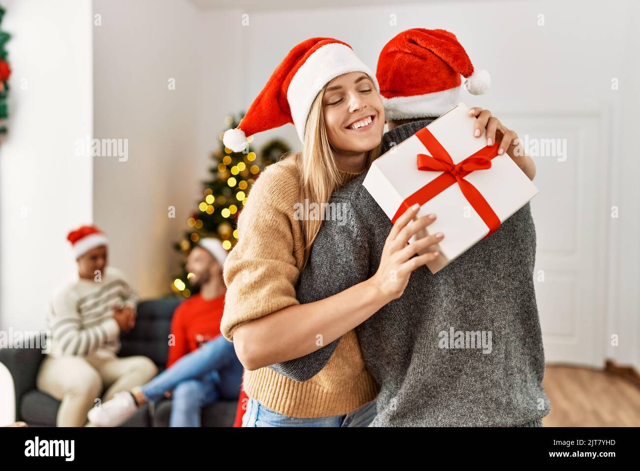 Group of young people on christmas meeting. Couple holding gift and ...