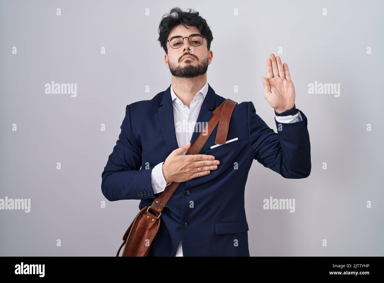 Hispanic man with beard wearing business clothes swearing with hand on ...