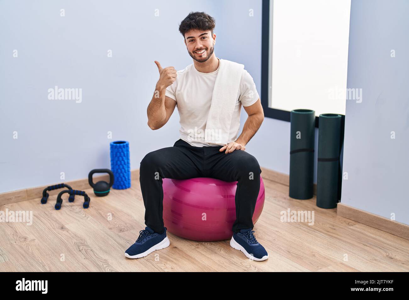 Hispanic man with beard sitting on pilate balls at yoga room doing ...