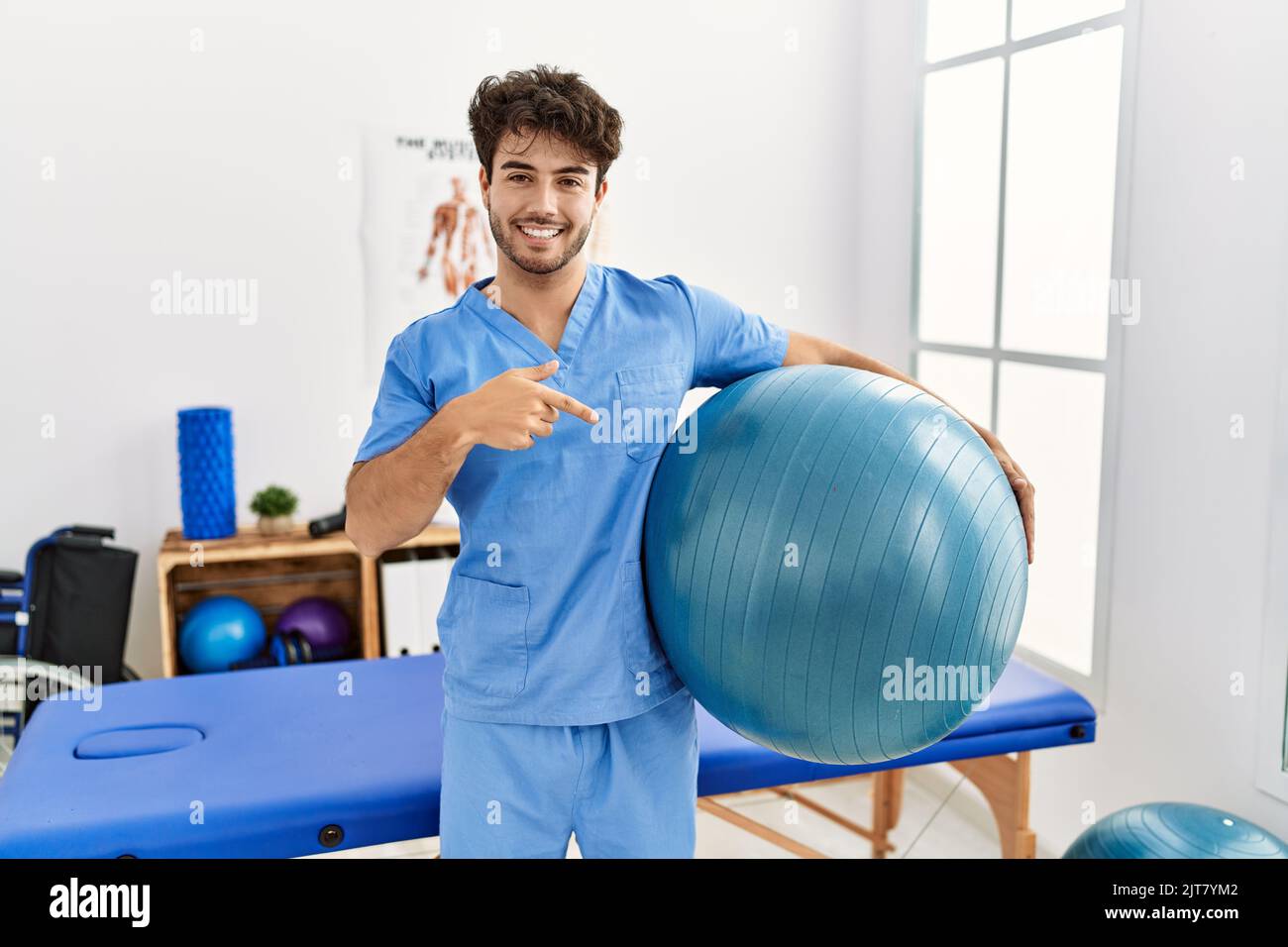Hispanic physiotherapy man working at pain recovery clinic smiling ...