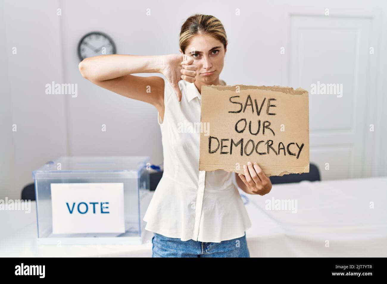 Young blonde woman at political election holding save out democracy ...