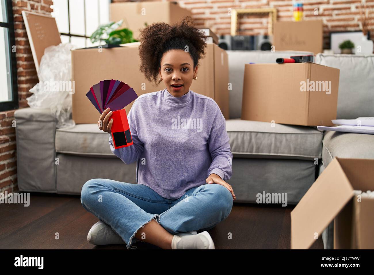 Young african american woman moving to a new home choosing colors ...
