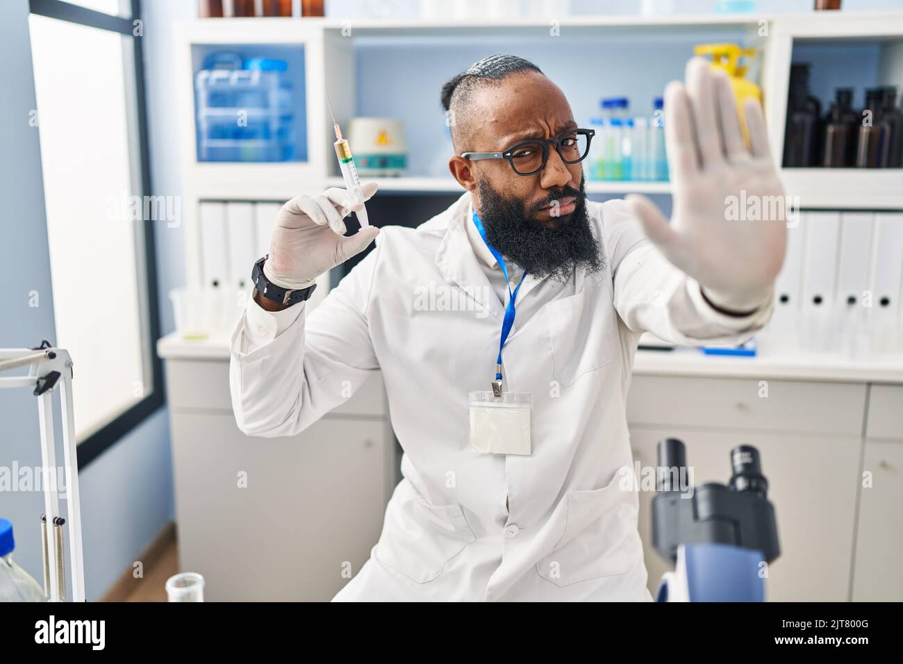 African american man working at scientist laboratory holding syringe ...