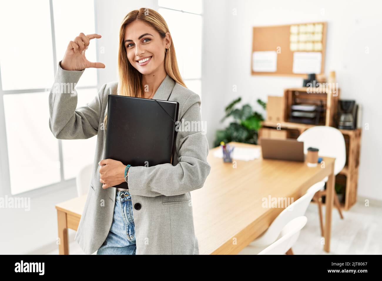Blonde business woman at the office smiling and confident gesturing ...