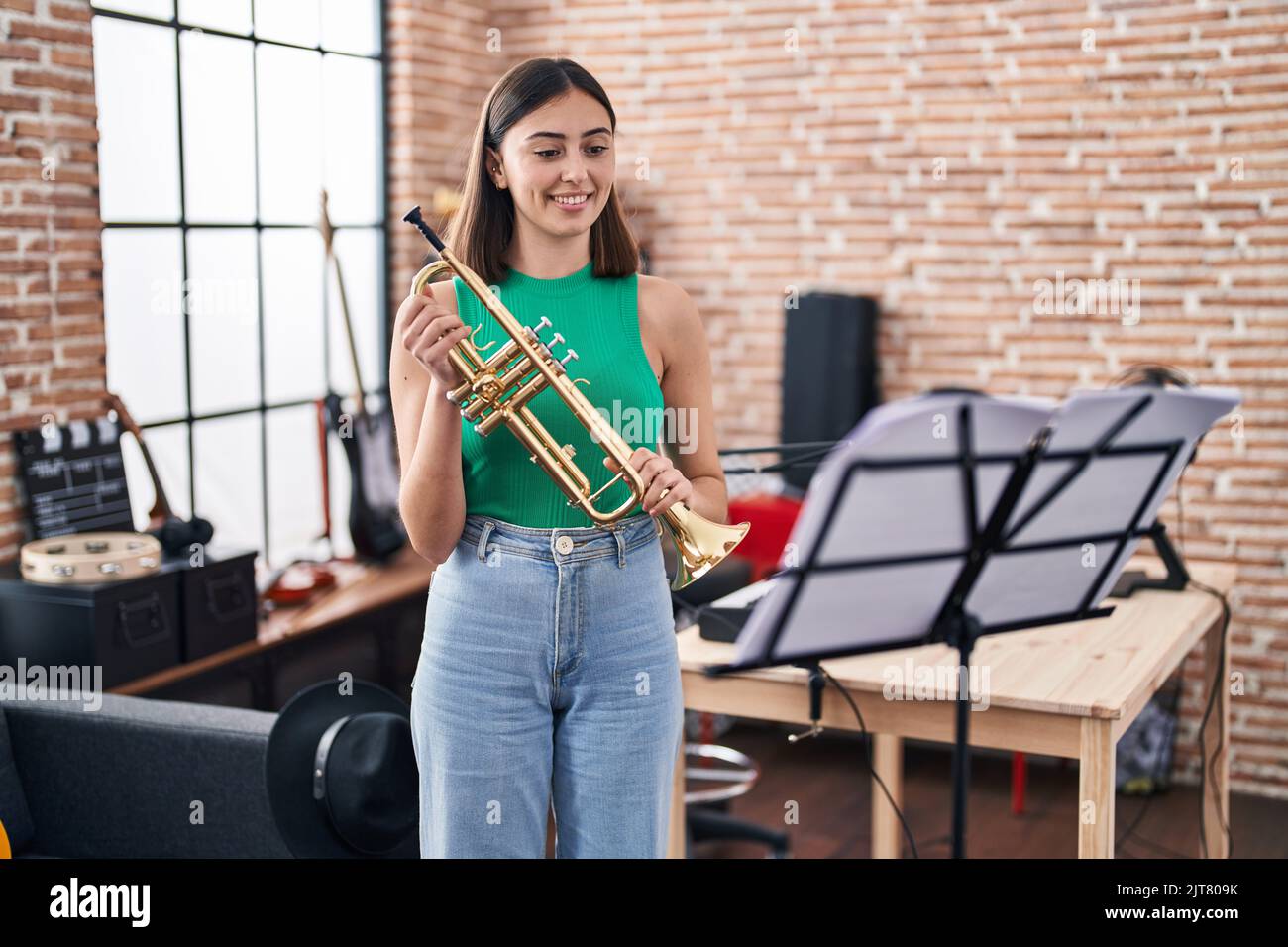 Young hispanic woman musician holding trumpet at music studio Stock ...
