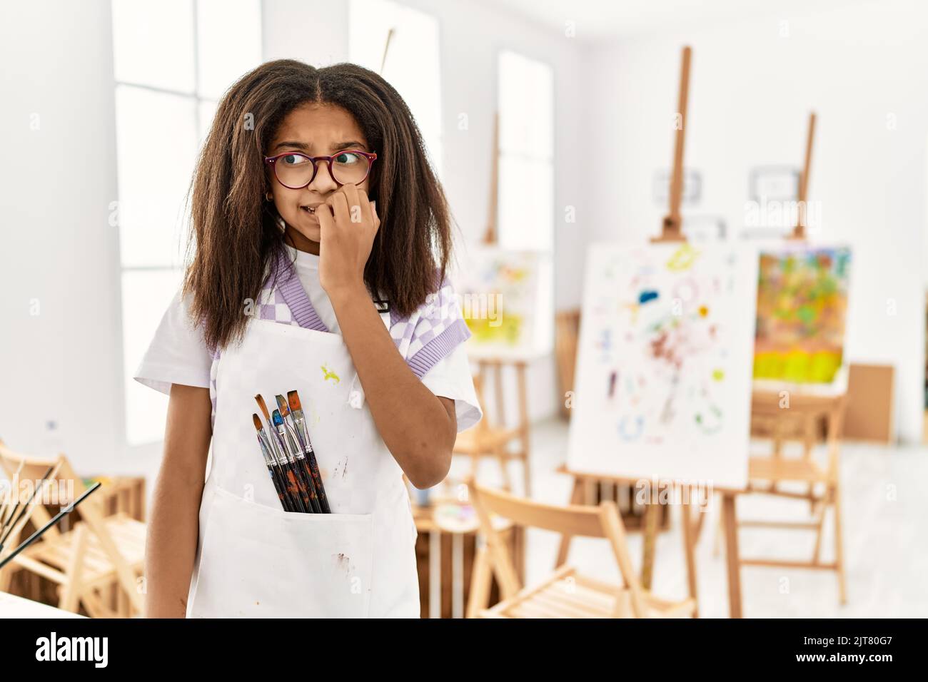 Young african american girl painting at art studio looking stressed and ...