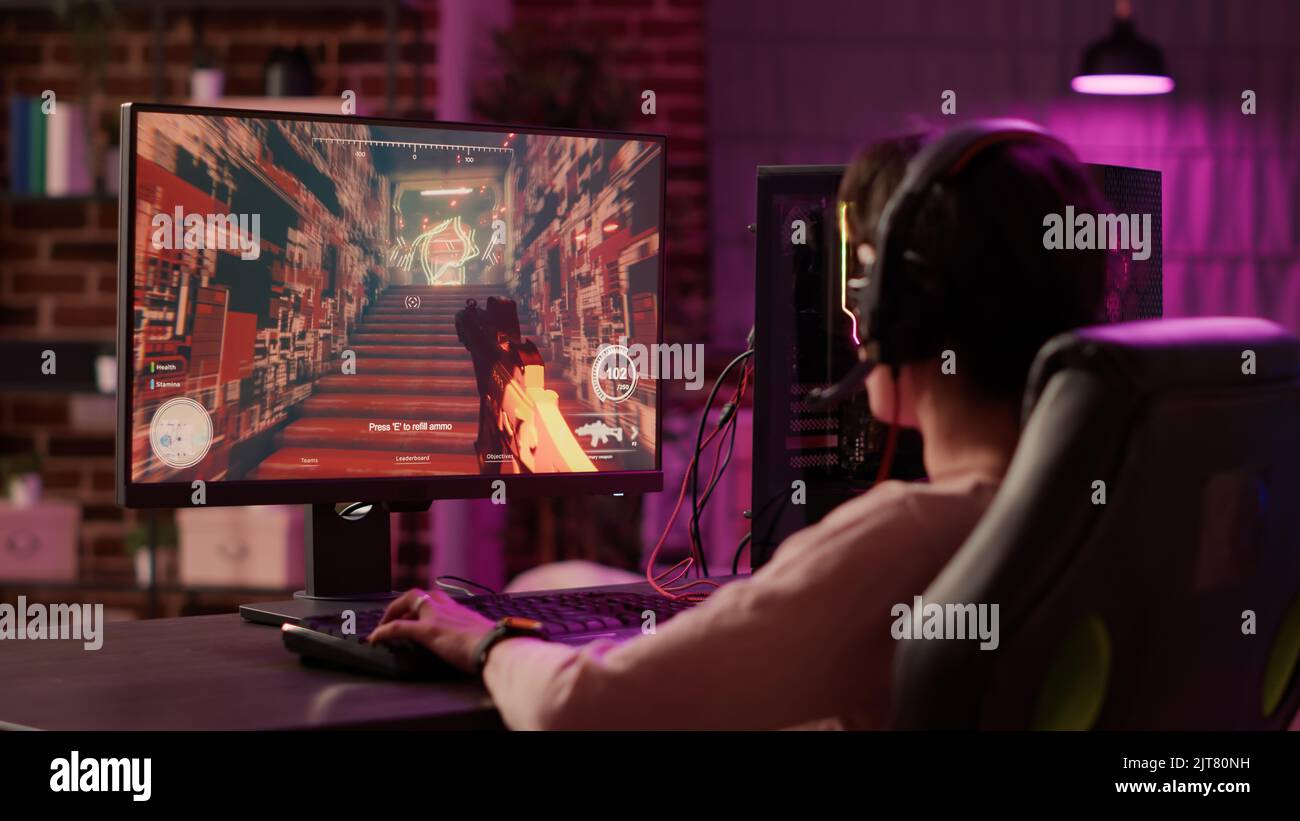 Over shoulder view of gamer girl using pc gaming setup relaxing playing ...