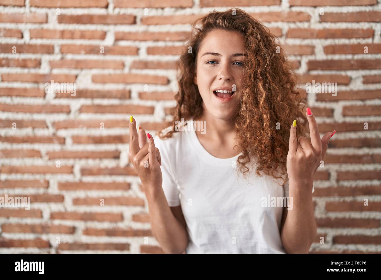 Young caucasian woman standing over bricks wall background shouting ...