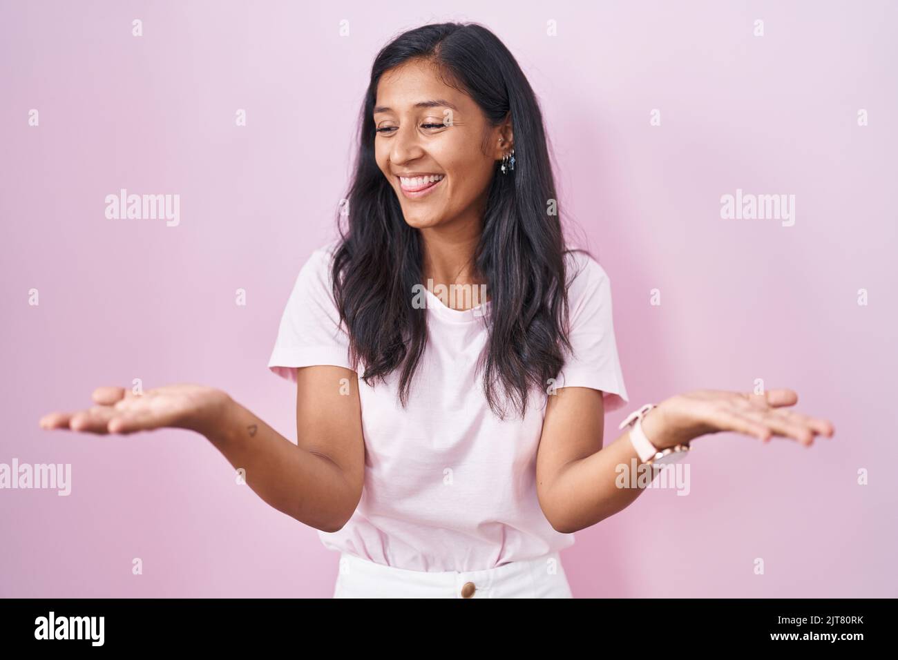 Young hispanic woman standing over pink background smiling showing both ...