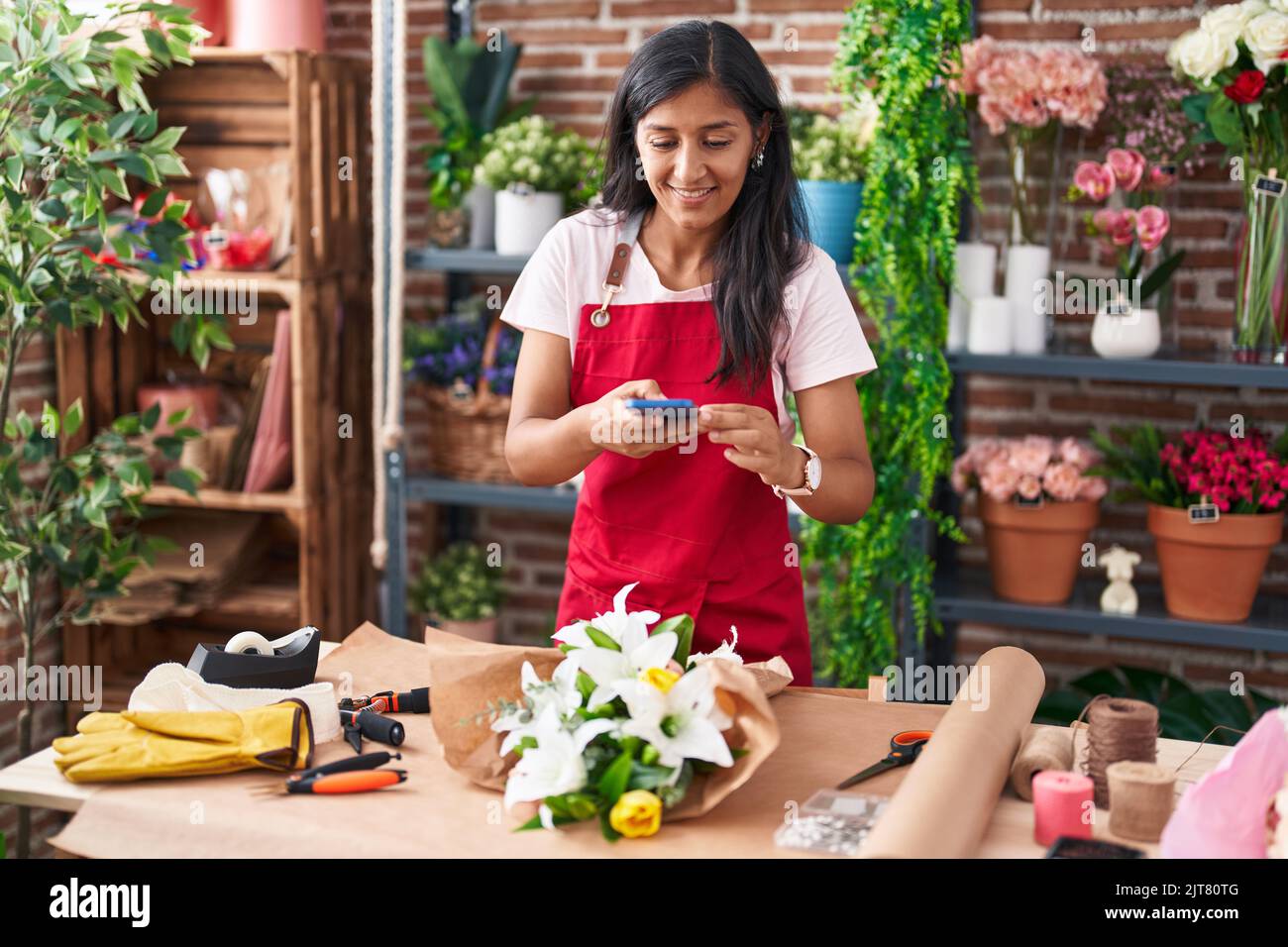 Young beautiful hispanic woman florist make photo to flower by ...