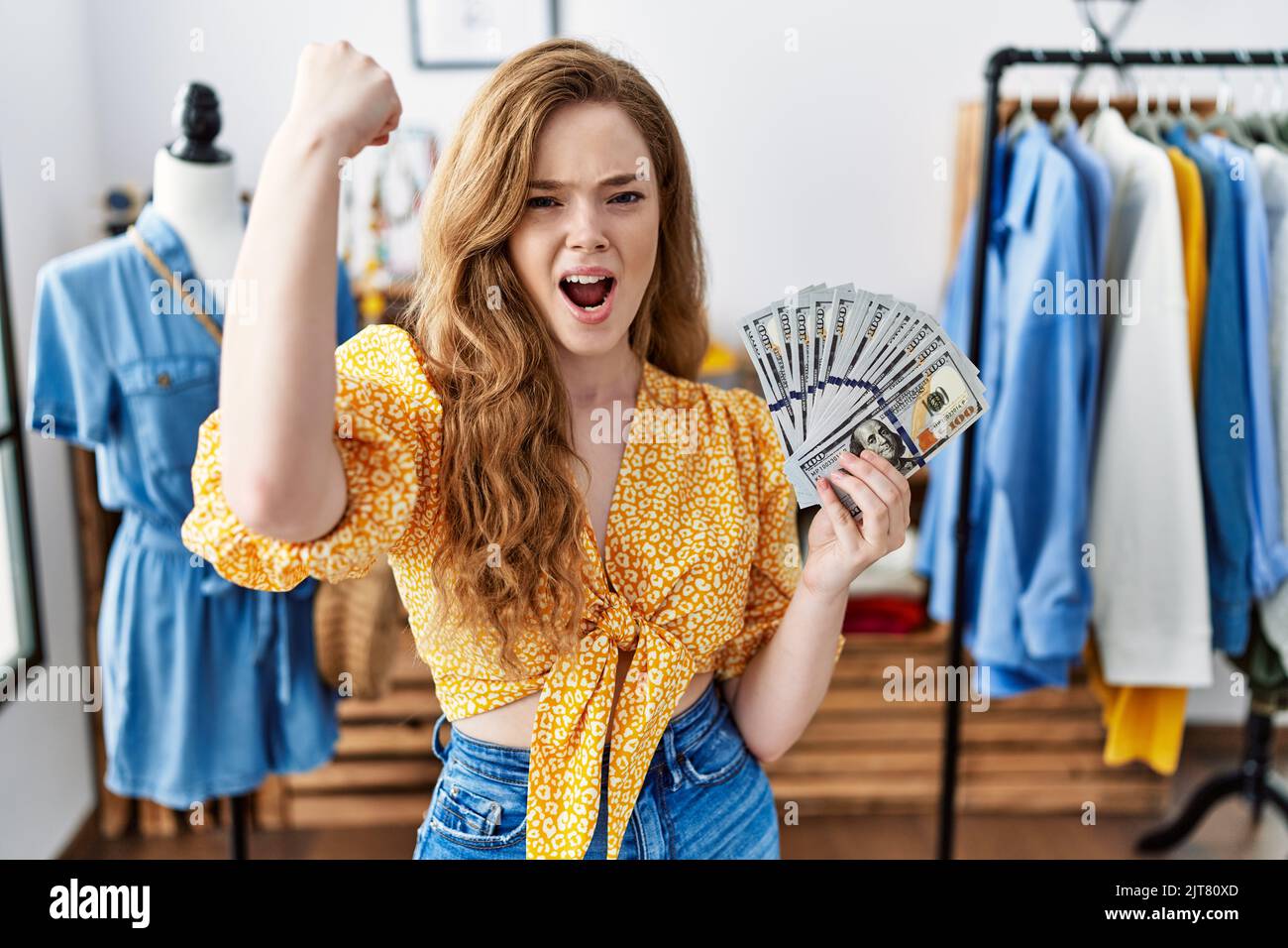 Young caucasian woman at retail boutique holding dollars banknotes ...