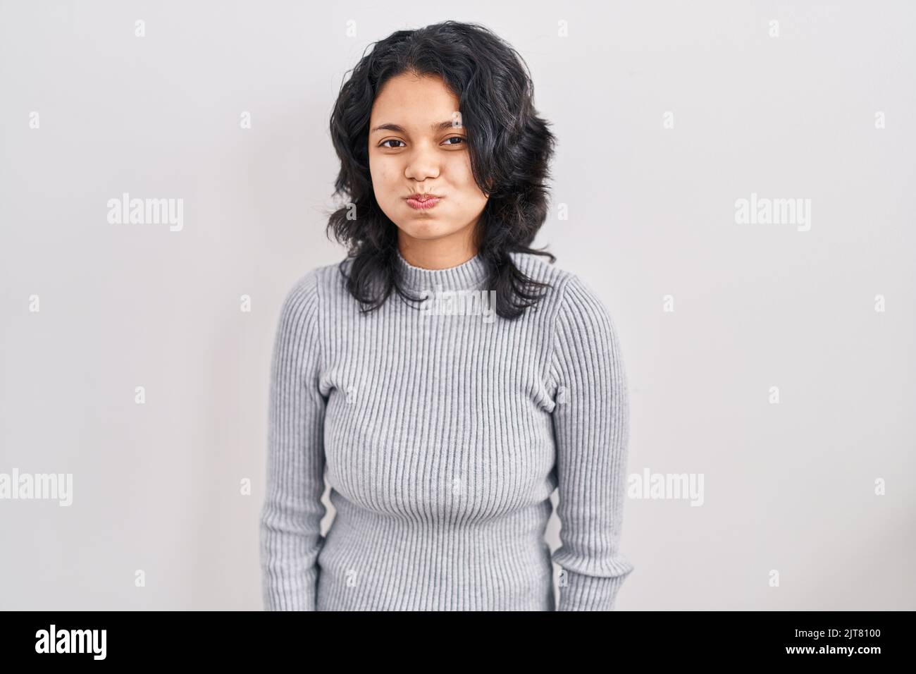 Hispanic woman with dark hair standing over isolated background puffing ...