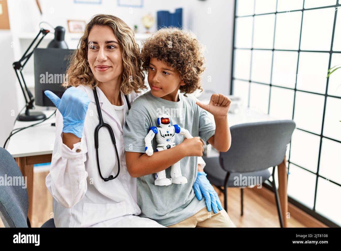 Young kid at pediatrician clinic holding teddy bear pointing thumb up ...
