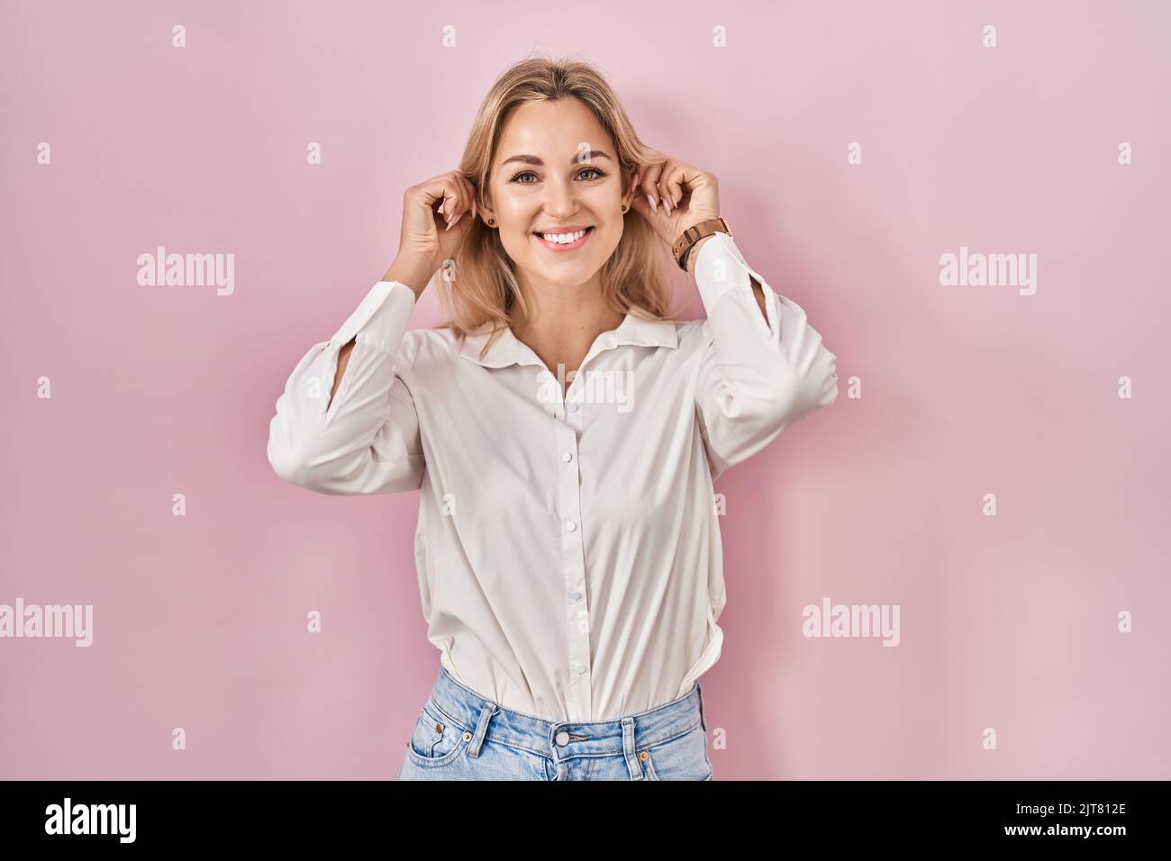 Young caucasian woman wearing casual white shirt over pink background ...