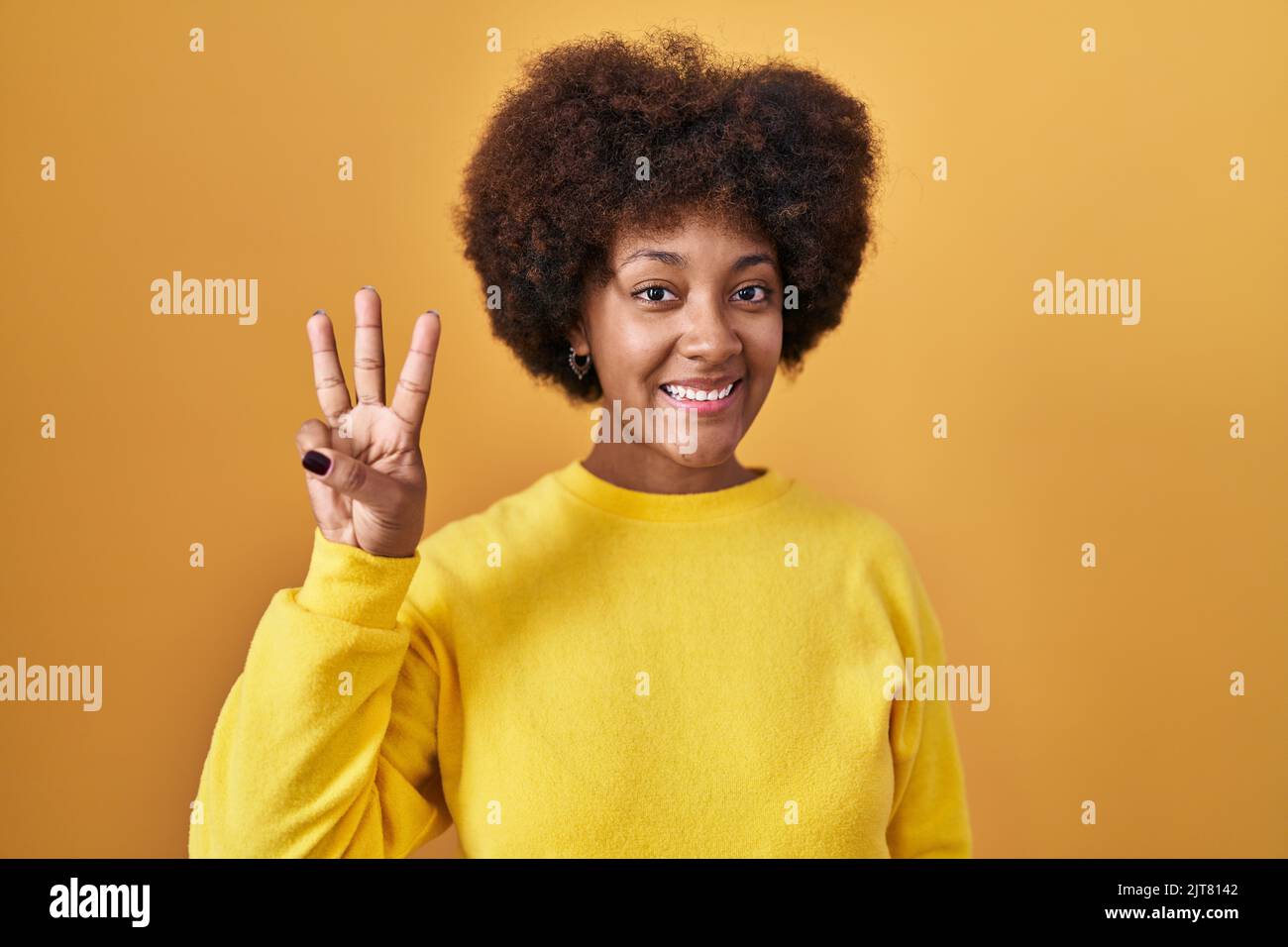 Young african american woman standing over yellow background showing ...
