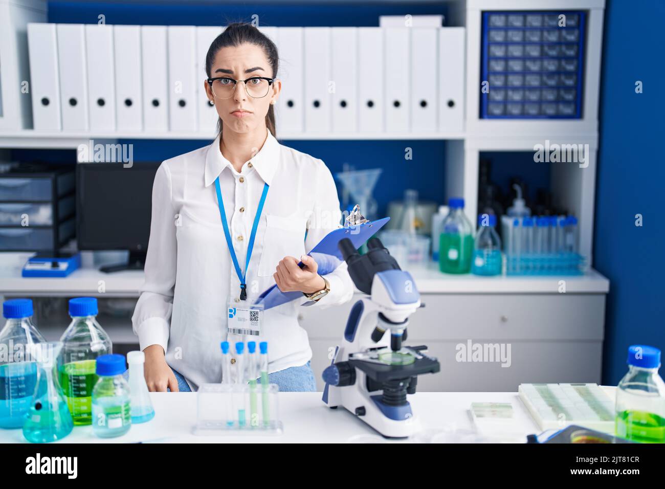 Young brunette woman working at scientist laboratory depressed and worry for distress, crying ...