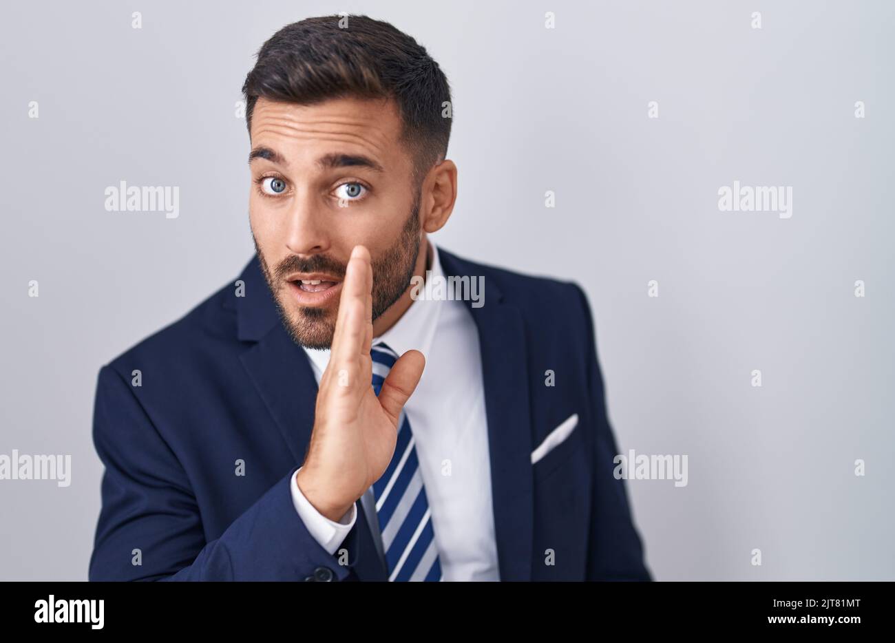 Handsome hispanic man wearing suit and tie hand on mouth telling secret ...