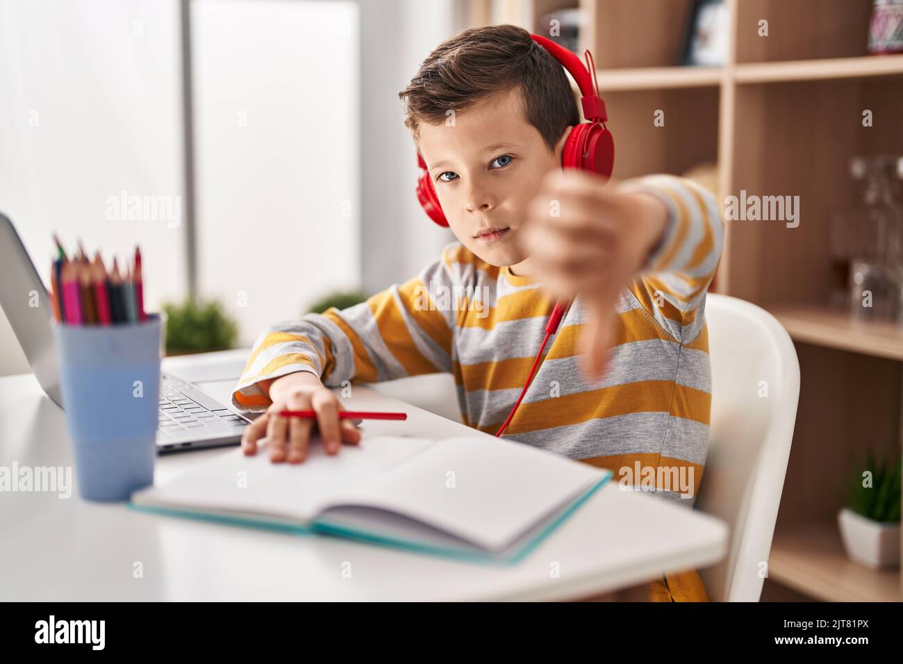 Young caucasian kid doing homework at home with angry face, negative ...