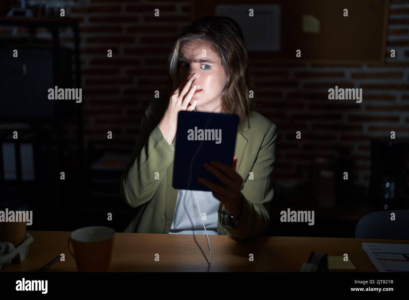 Blonde caucasian woman working at the office at night smelling ...