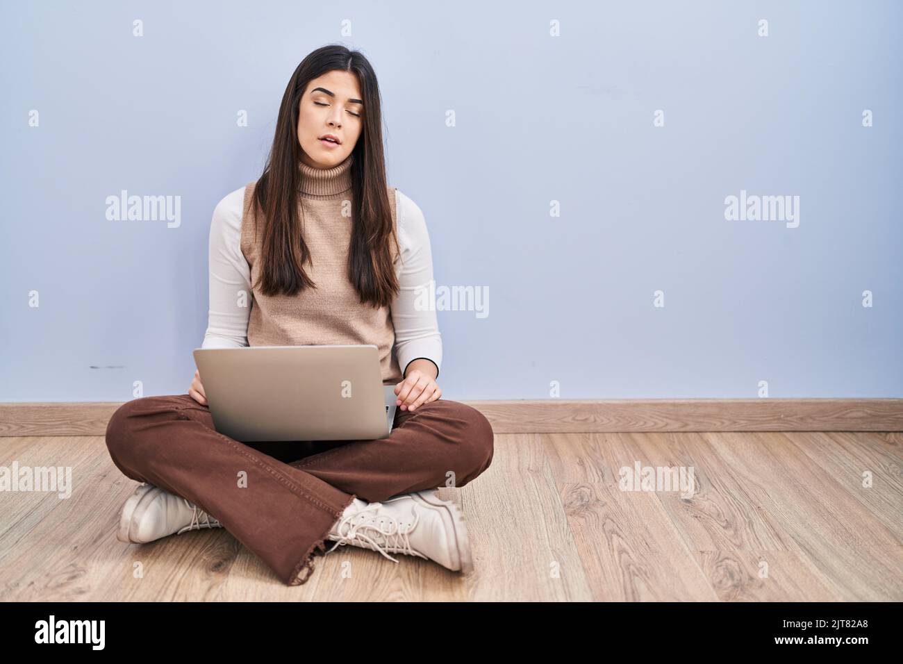 Young brunette woman working using computer laptop sitting on the floor ...