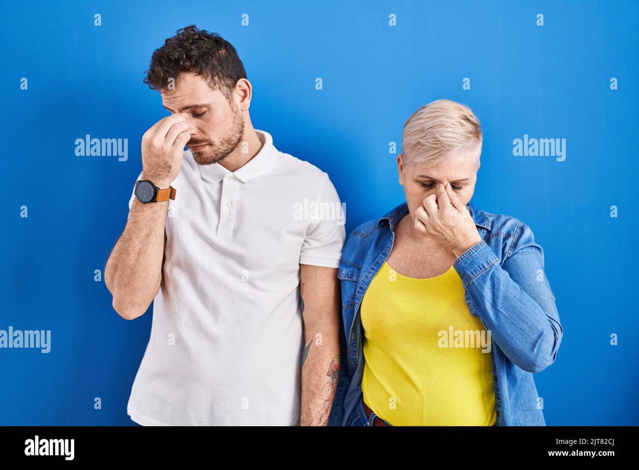 Young brazilian mother and son standing over blue background tired ...