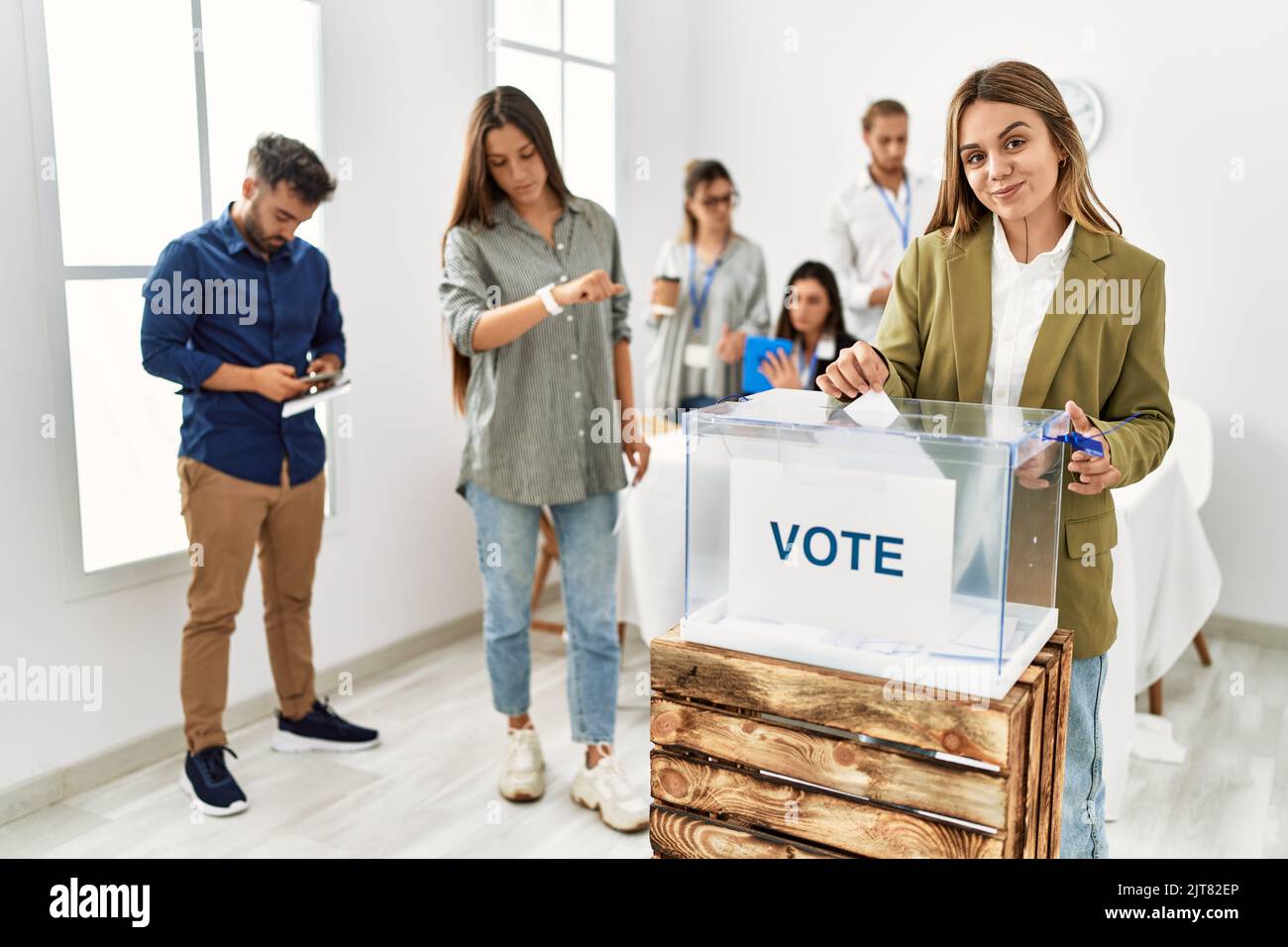Young voter woman smiling happy putting vote in voting box at electoral ...