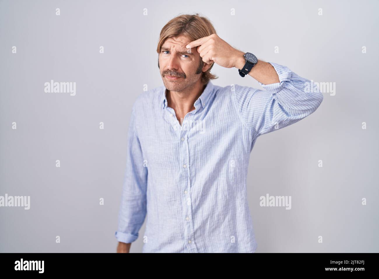 Caucasian man with mustache standing over white background pointing ...