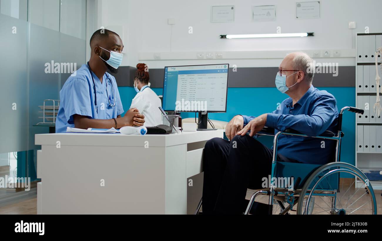 Male nurse doing checkup consultation with elderly man in wheelchair ...