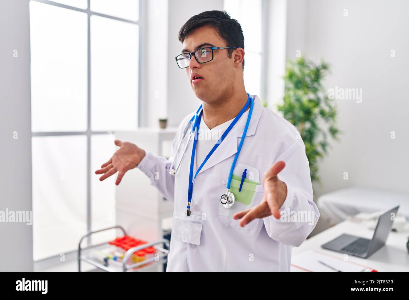 Down syndrome man wearing doctor uniform speaking at clinic Stock Photo ...