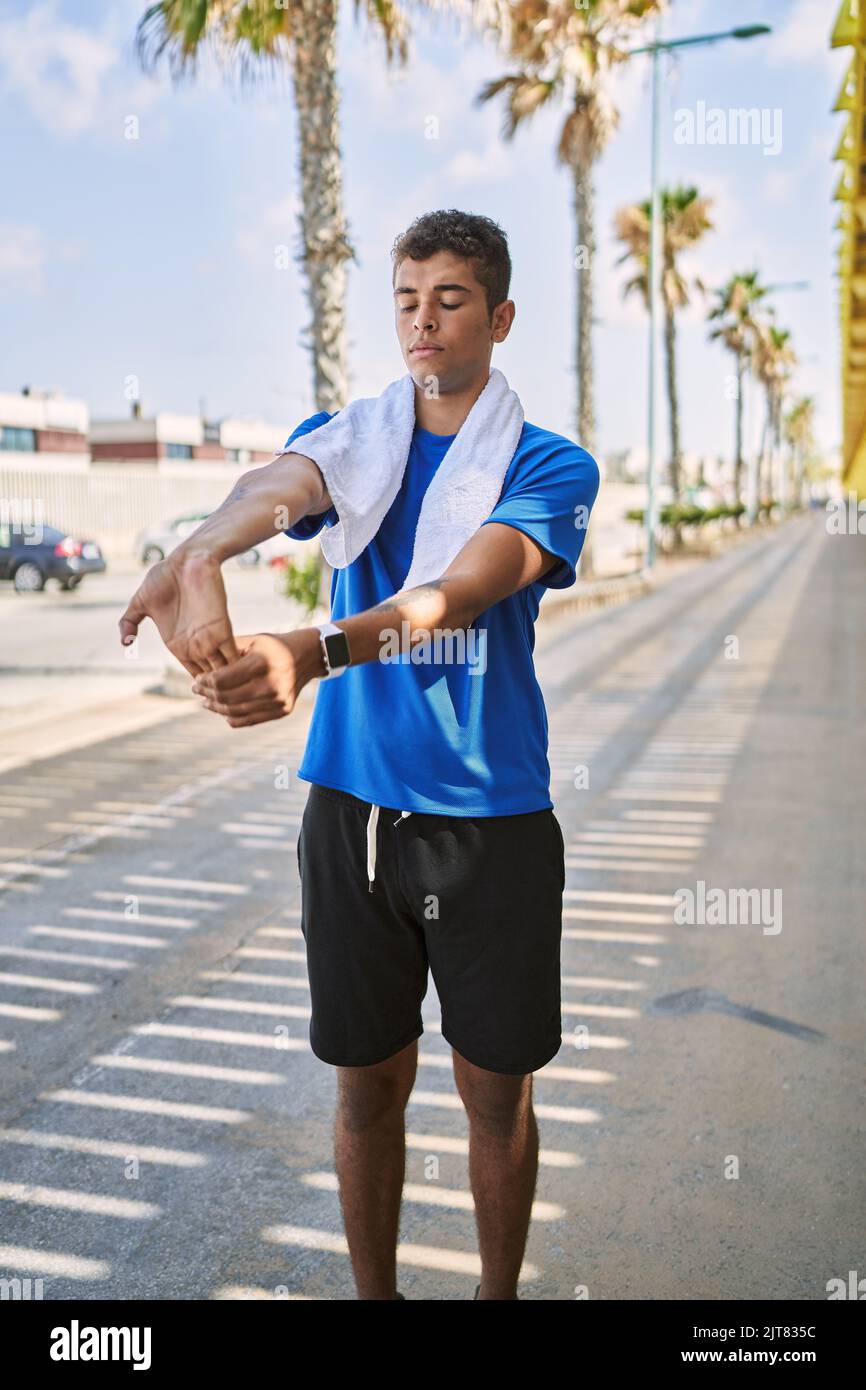 Young hispanic man stretching arms muscles outdoors Stock Photo - Alamy