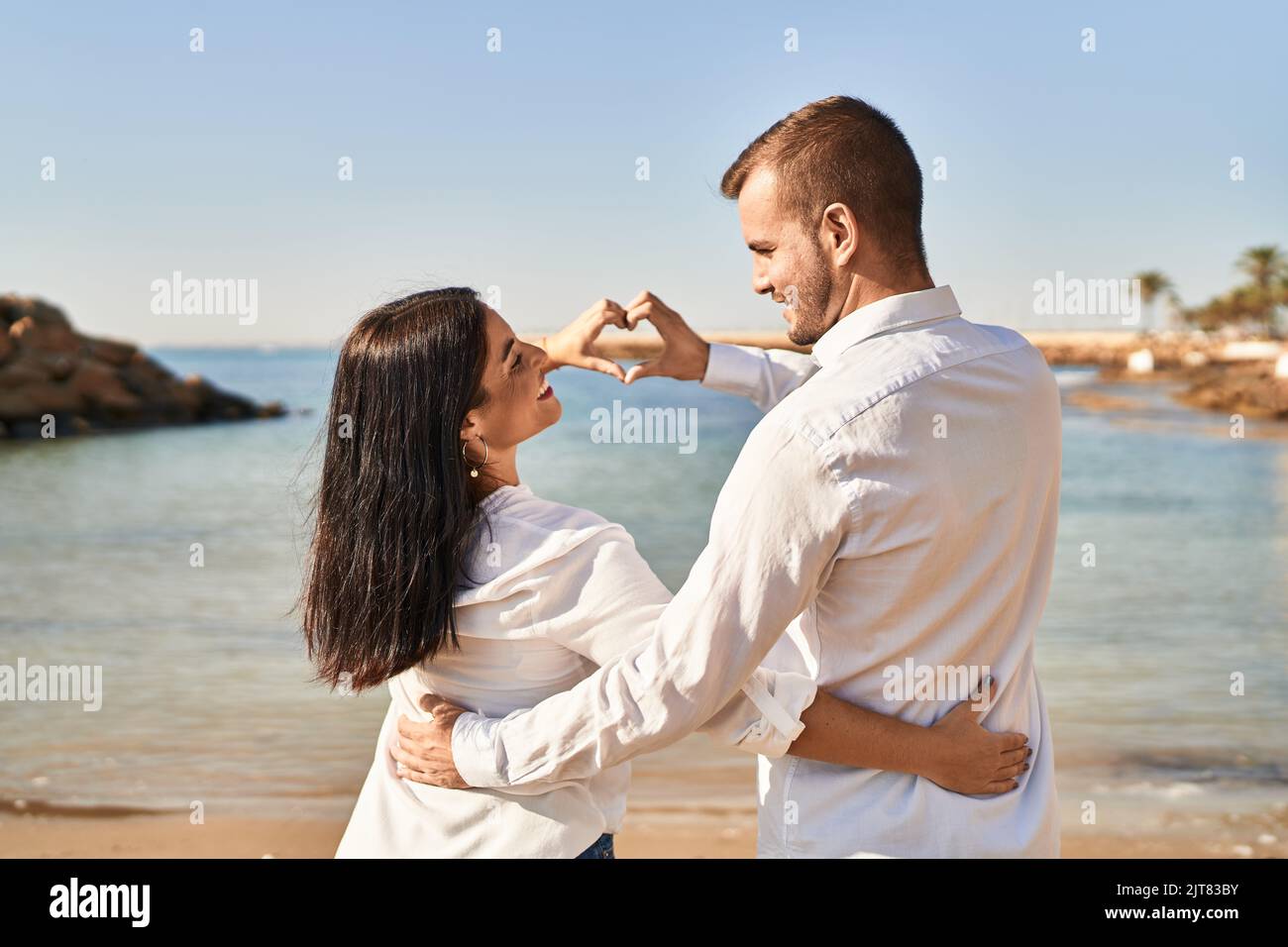 Man and woman couple on back view doing heart symbol with hands at ...