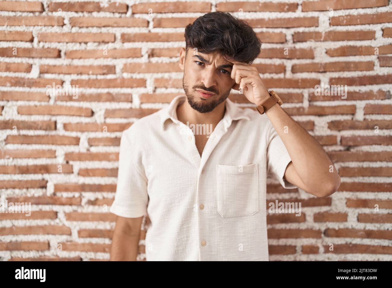Arab man with beard standing over bricks wall background pointing ...