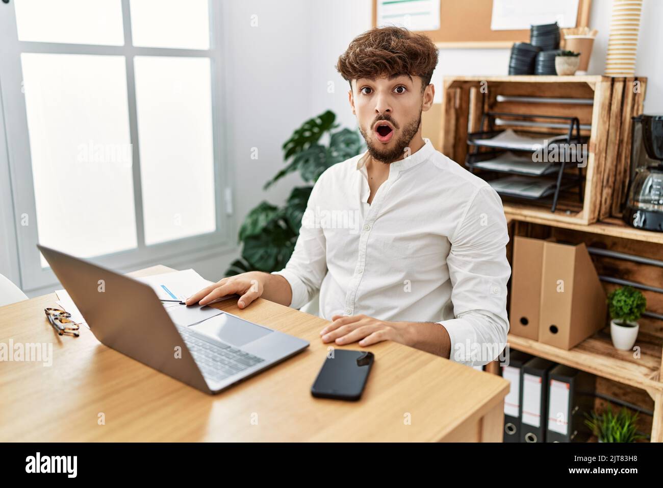 Young arab man working using computer laptop at the office scared and ...