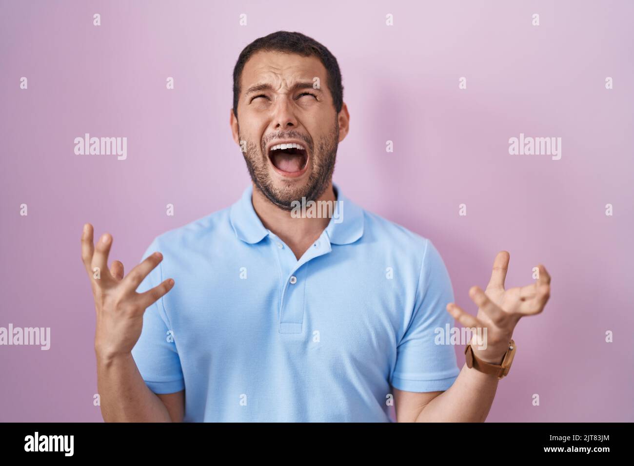 Hispanic man standing over pink background crazy and mad shouting and ...
