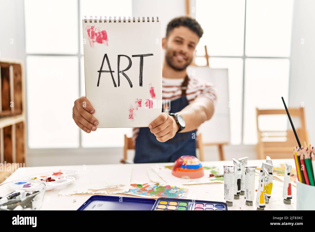 Young arab artist man smiling happy holding notebook with art word at ...