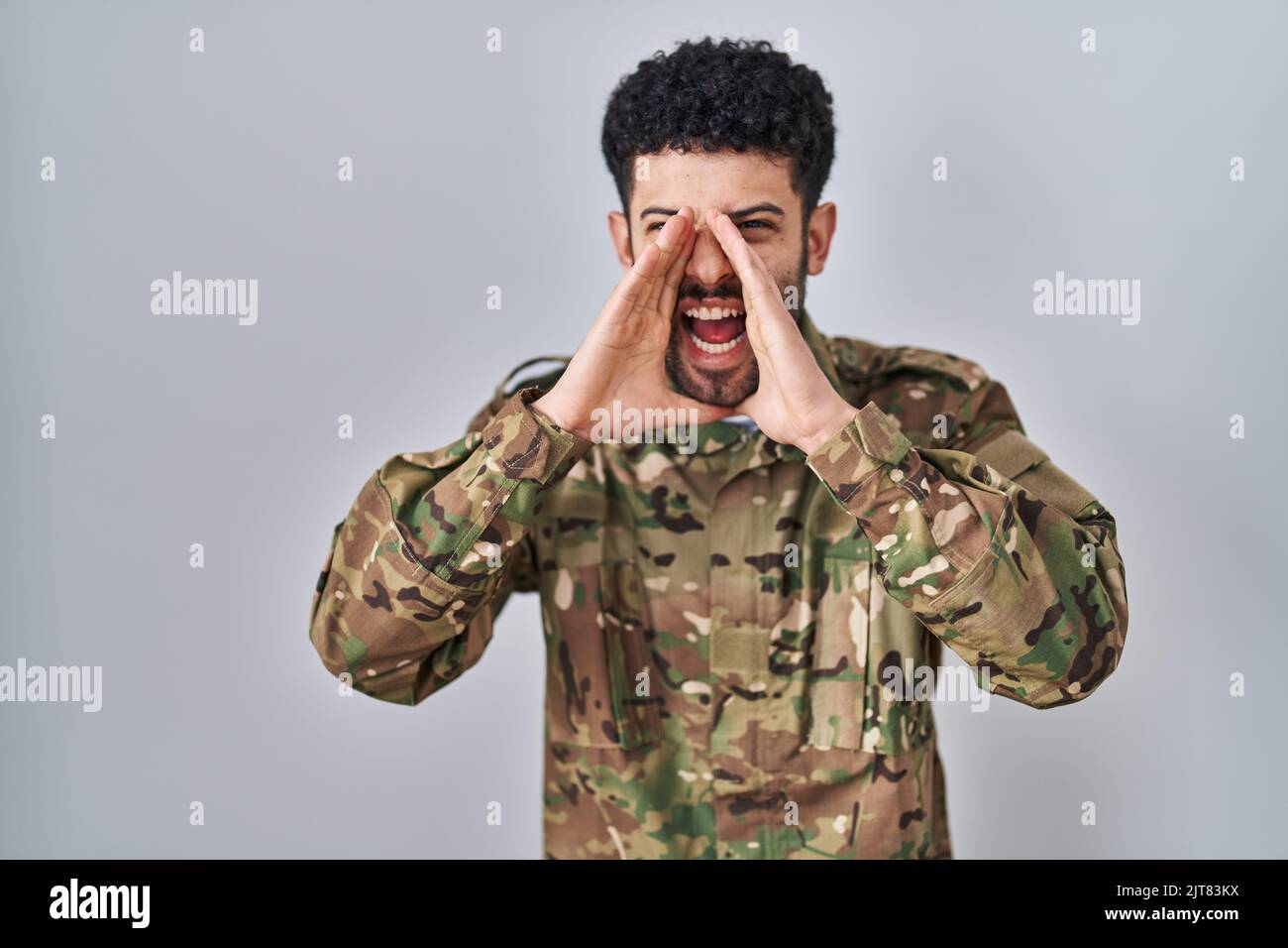 Arab man wearing camouflage army uniform shouting angry out loud with ...