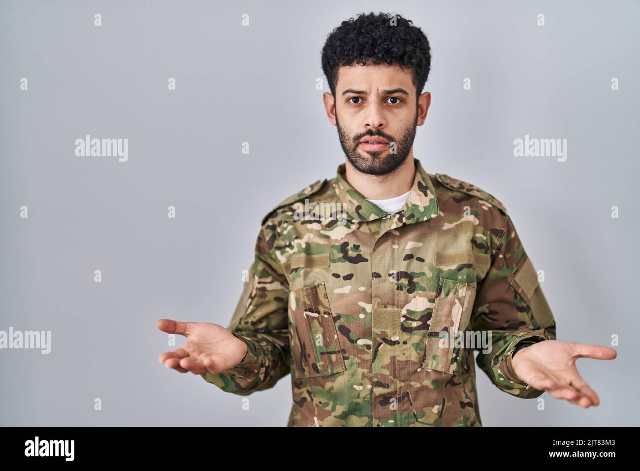 Arab man wearing camouflage army uniform clueless and confused with ...