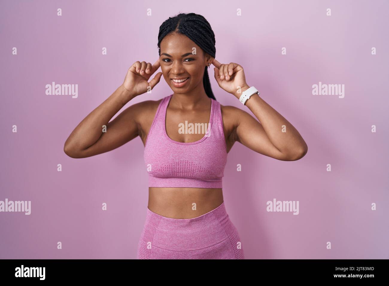 African american woman with braids wearing sportswear over pink ...