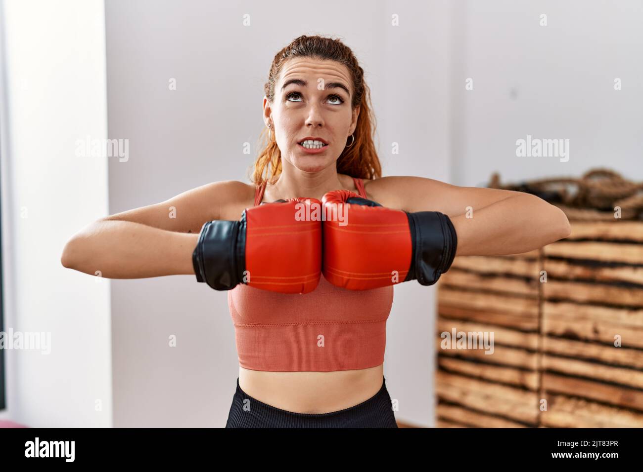 Young redhead woman using boxing gloves angry and mad screaming ...