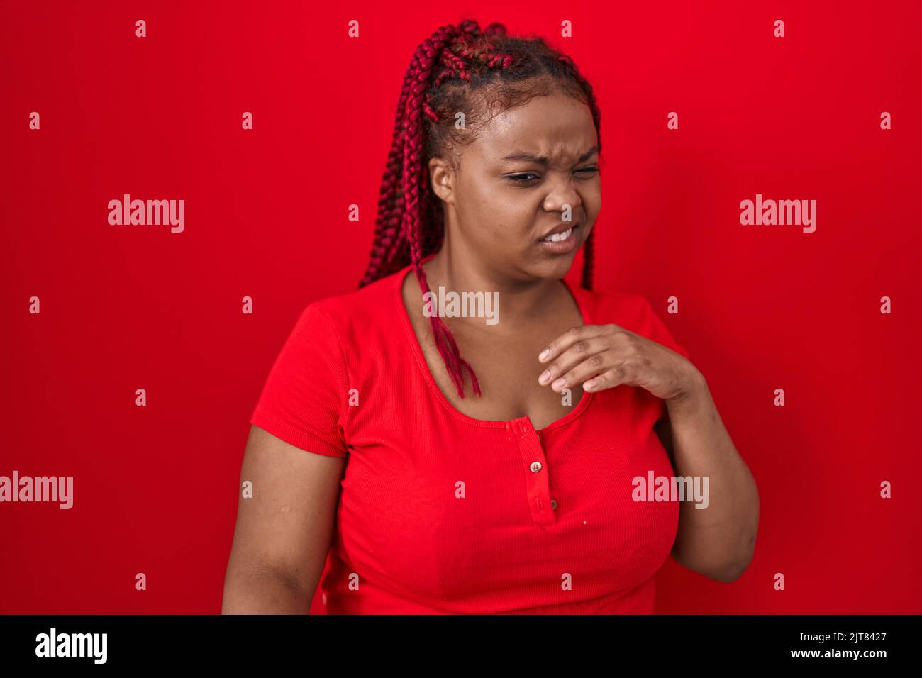 African american woman with braided hair standing over red background ...