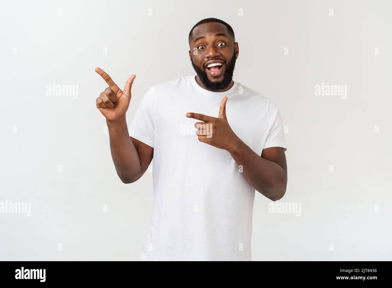 Young amazed African American pointing his finger at white background ...